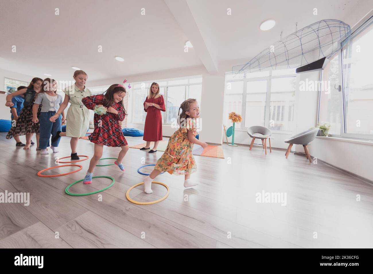 Small nursery school children with female teacher on floor indoors in ...
