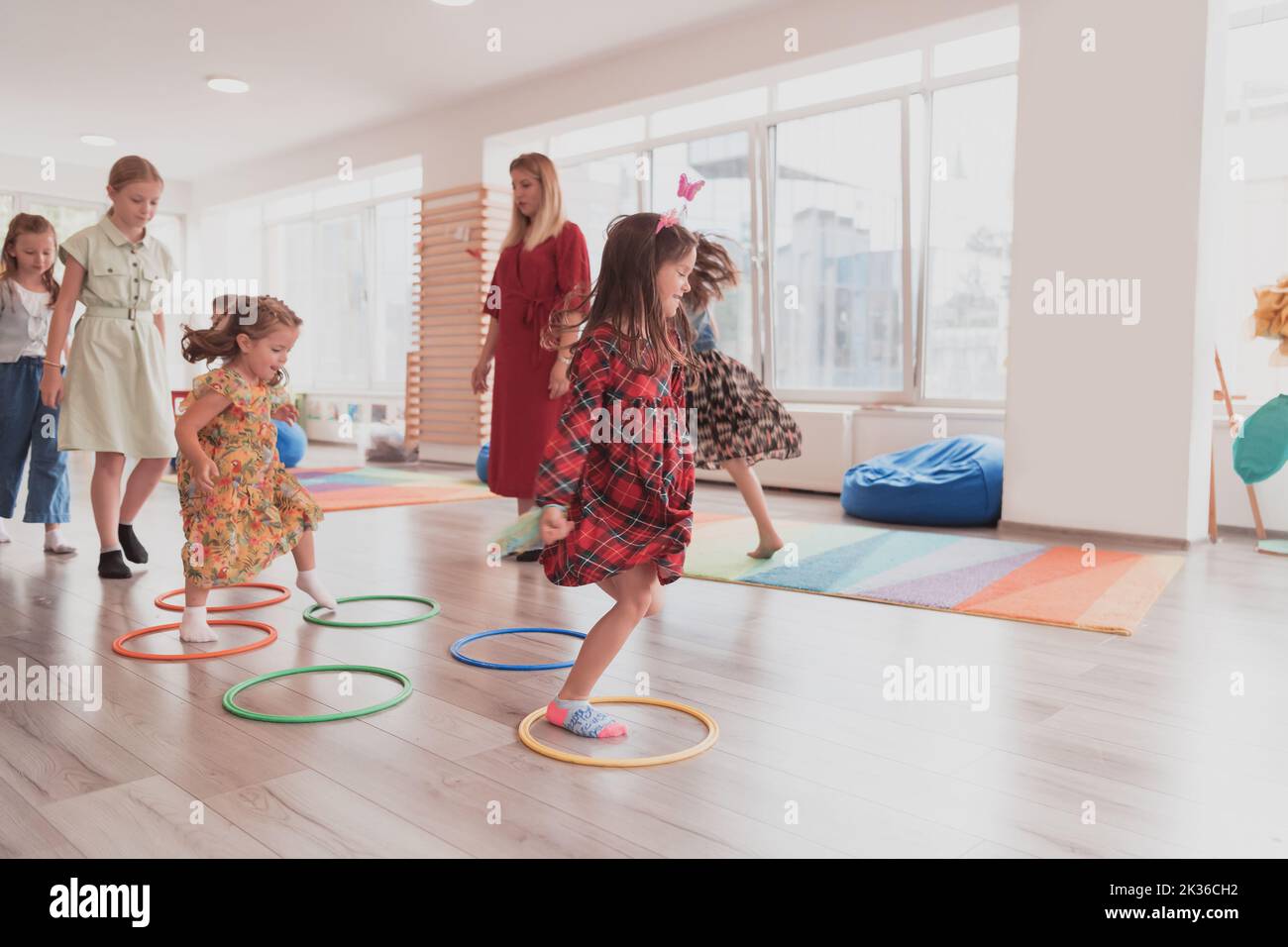 Small nursery school children with female teacher on floor indoors in ...