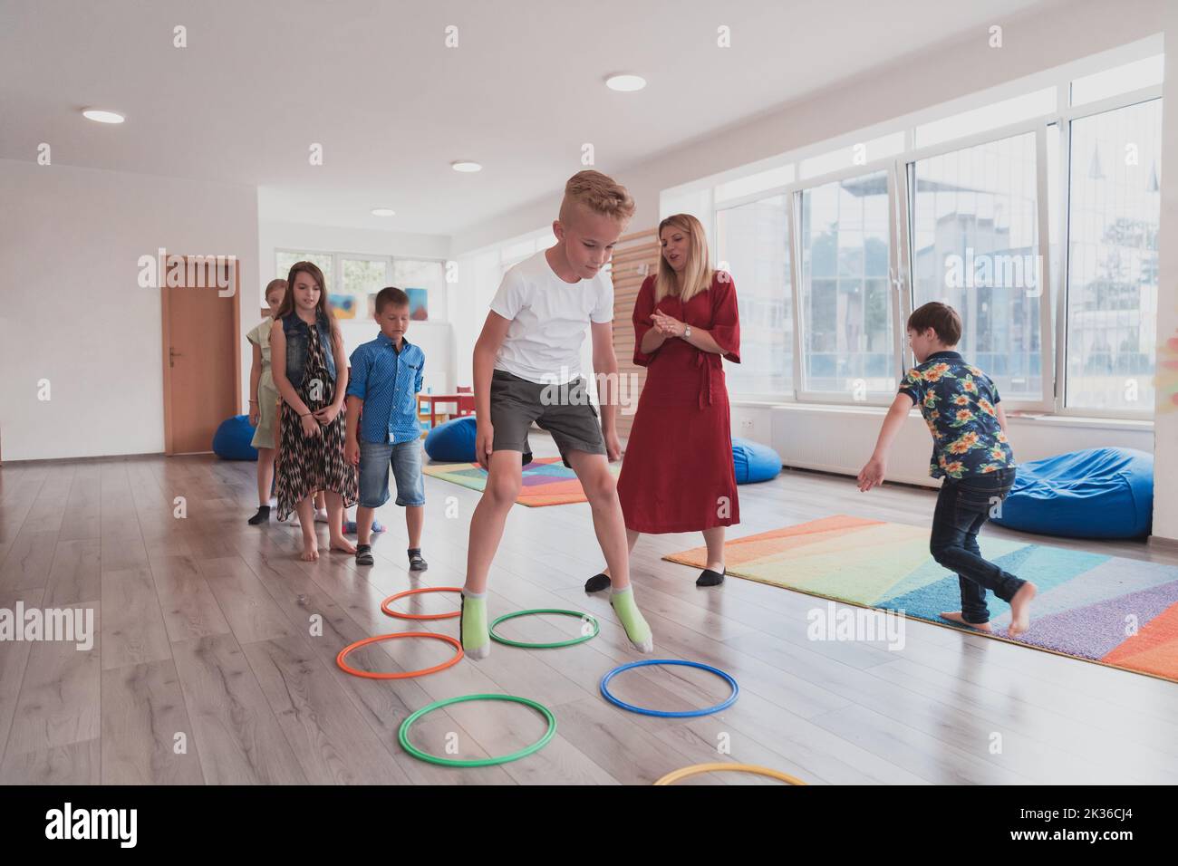 Small nursery school children with female teacher on floor indoors in ...