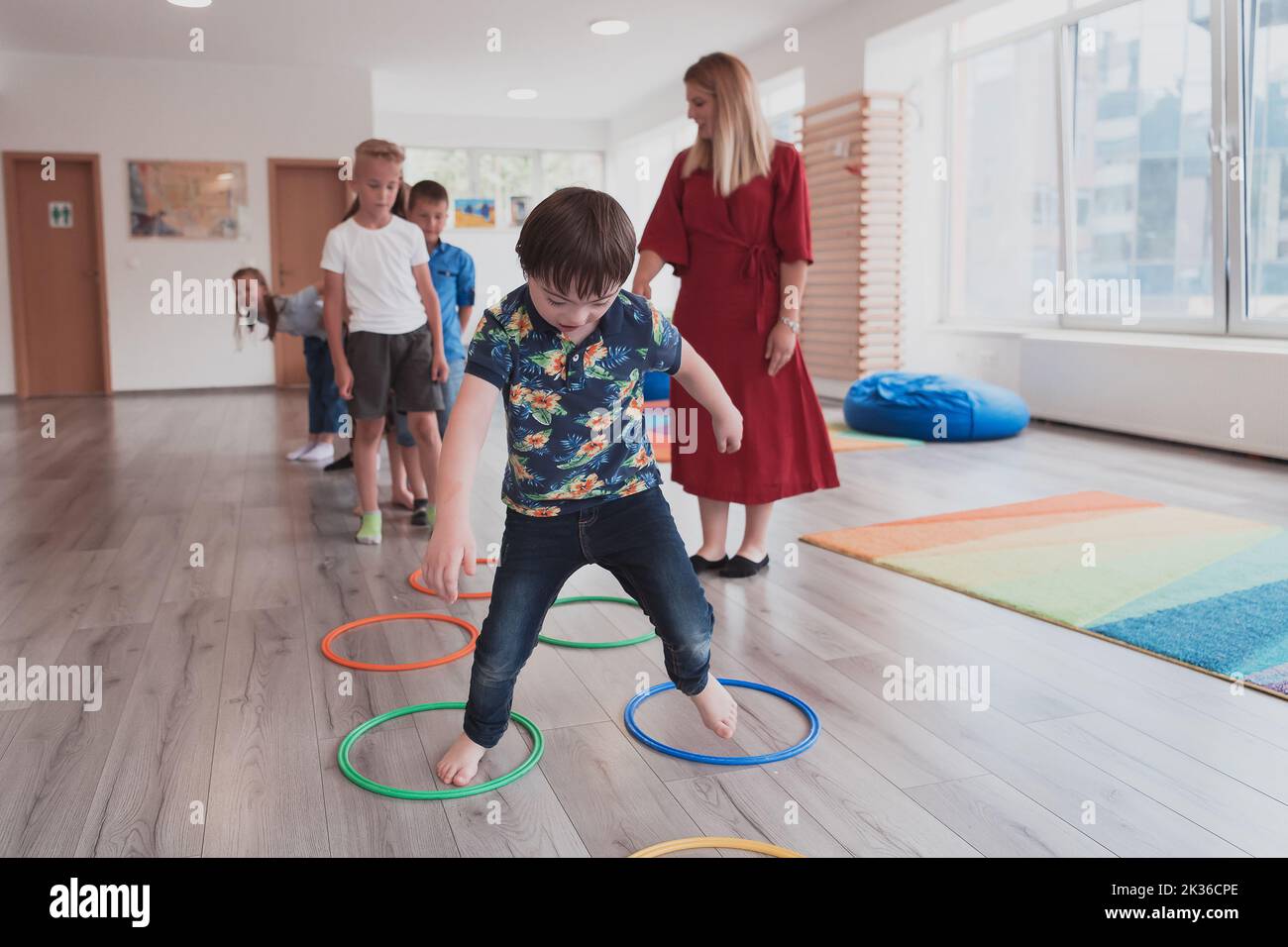 Small nursery school children with female teacher on floor indoors in ...