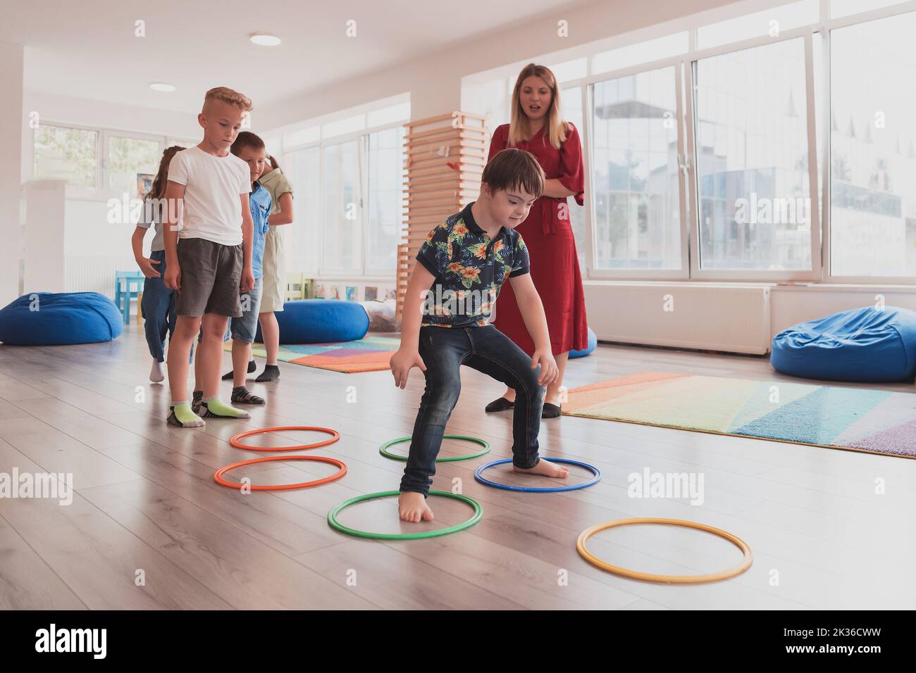 Small nursery school children with female teacher on floor indoors in ...