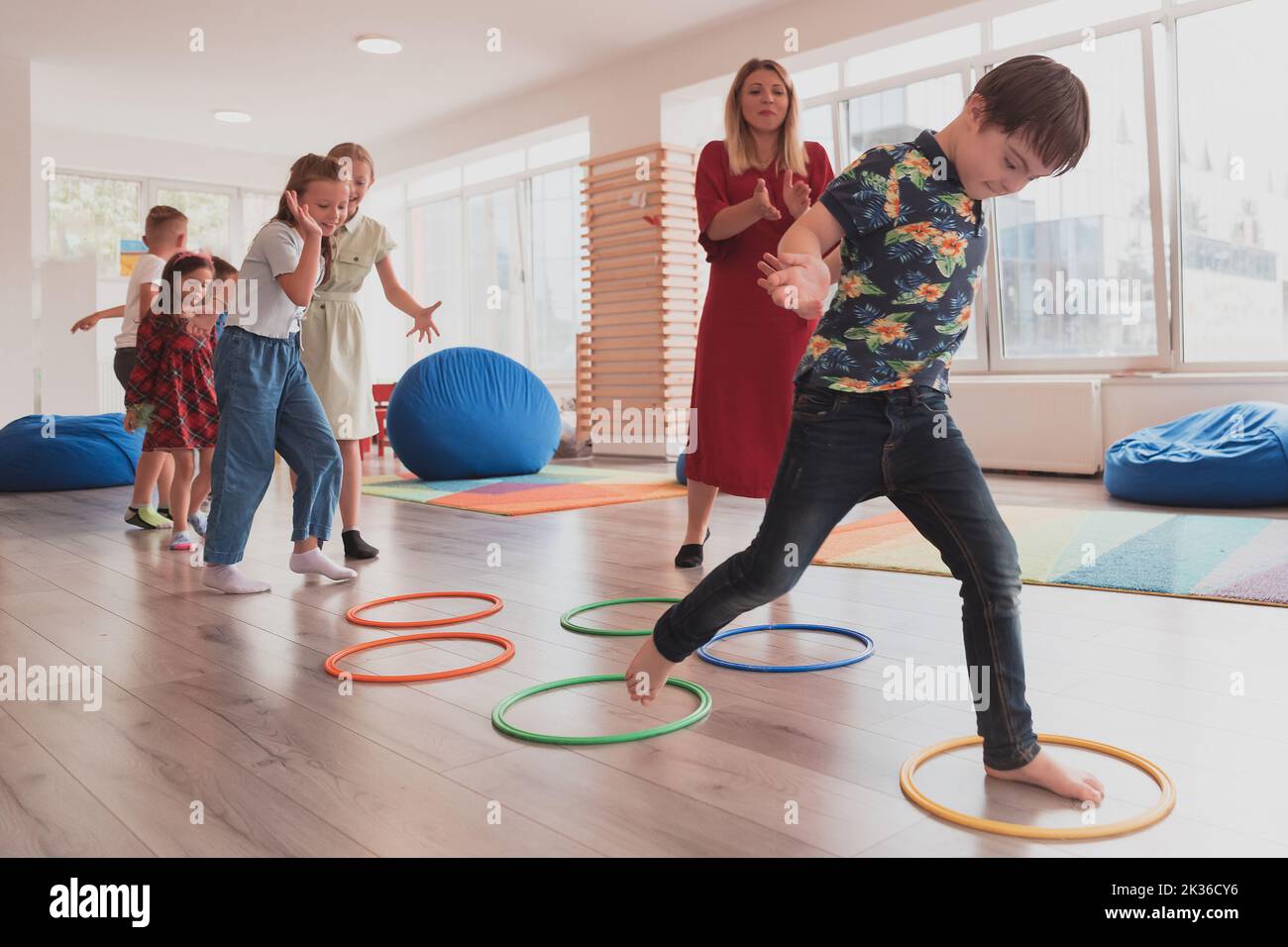 Small nursery school children with female teacher on floor indoors in ...