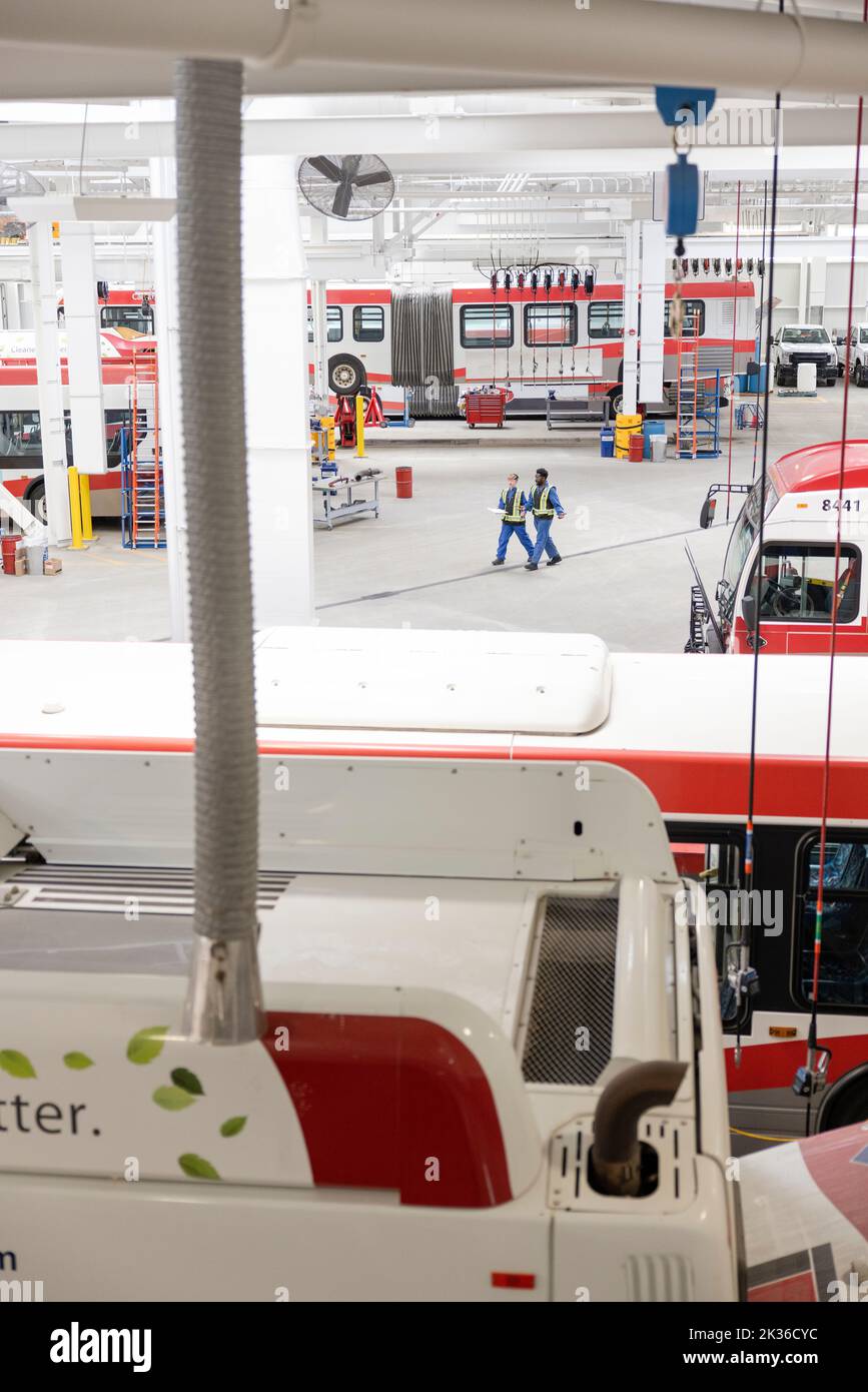 Workers walking in bus maintenance facility Stock Photo - Alamy
