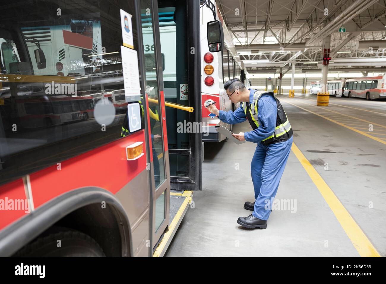 Male engineer inspecting bus in transit garage Stock Photo - Alamy