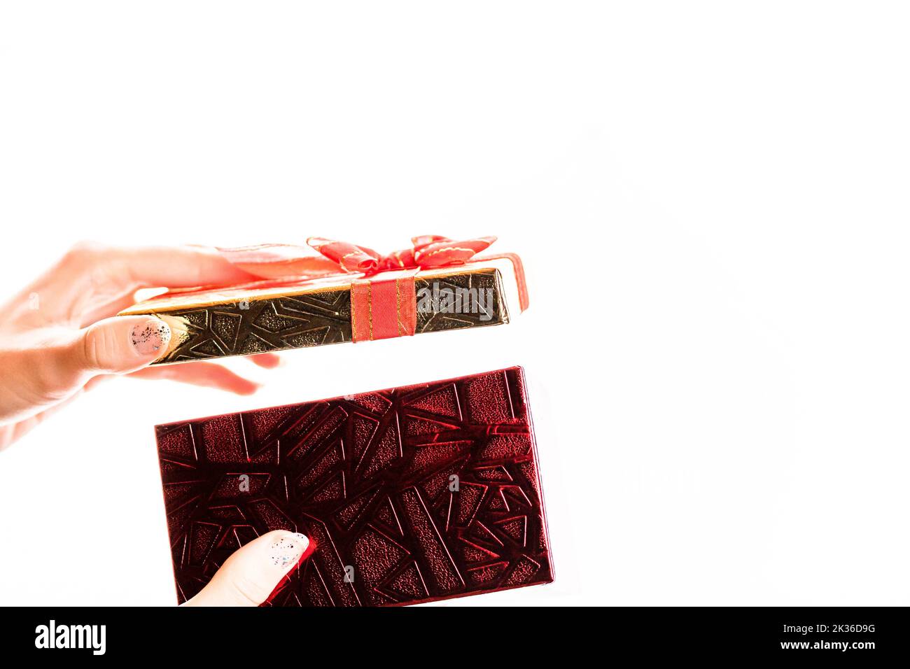 A human hand opening a black gift box with red bow isolated on white ...