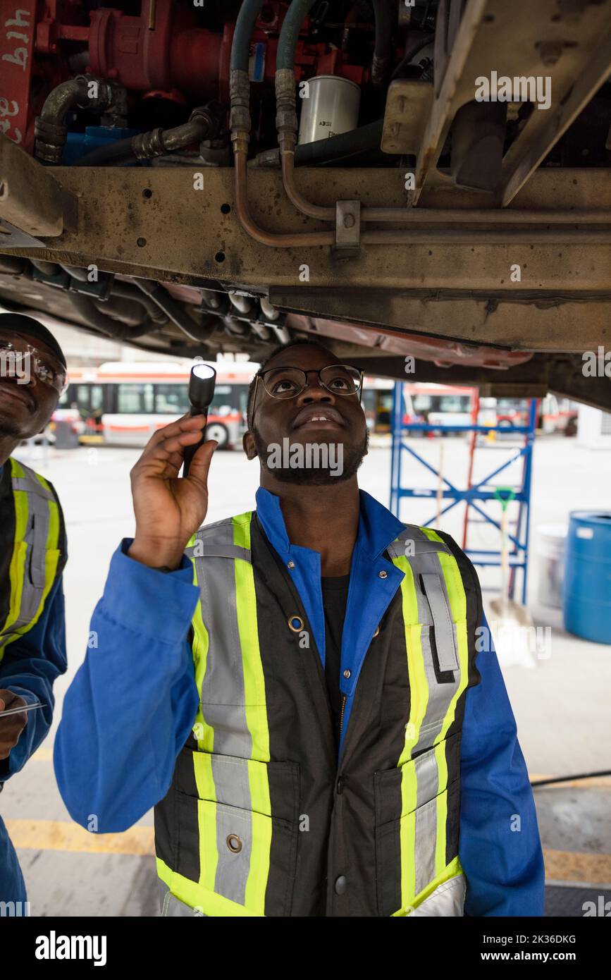 Male mechanic with flashlight under bus in maintenance facility Stock ...