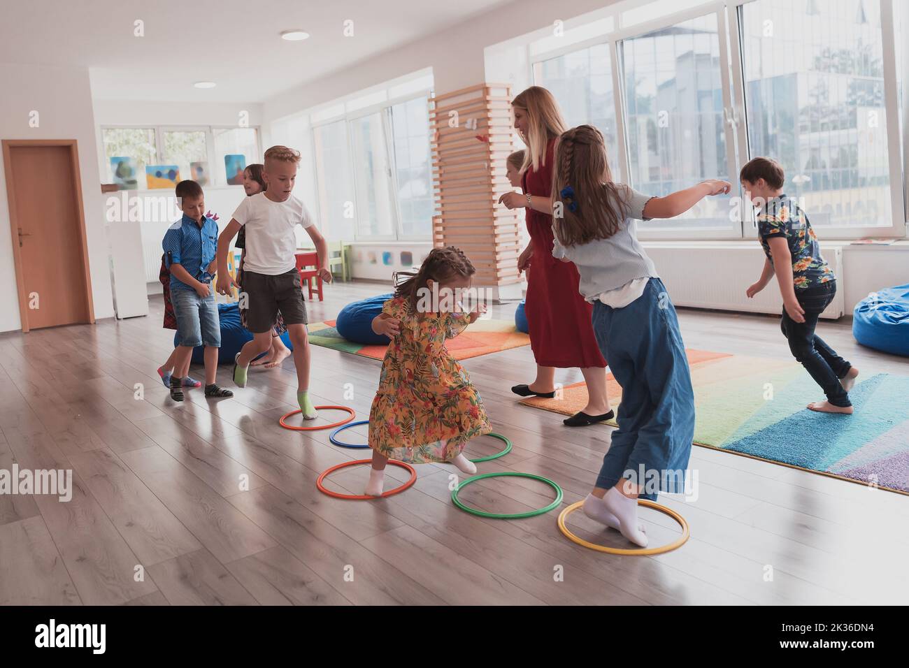 Small nursery school children with female teacher on floor indoors in ...
