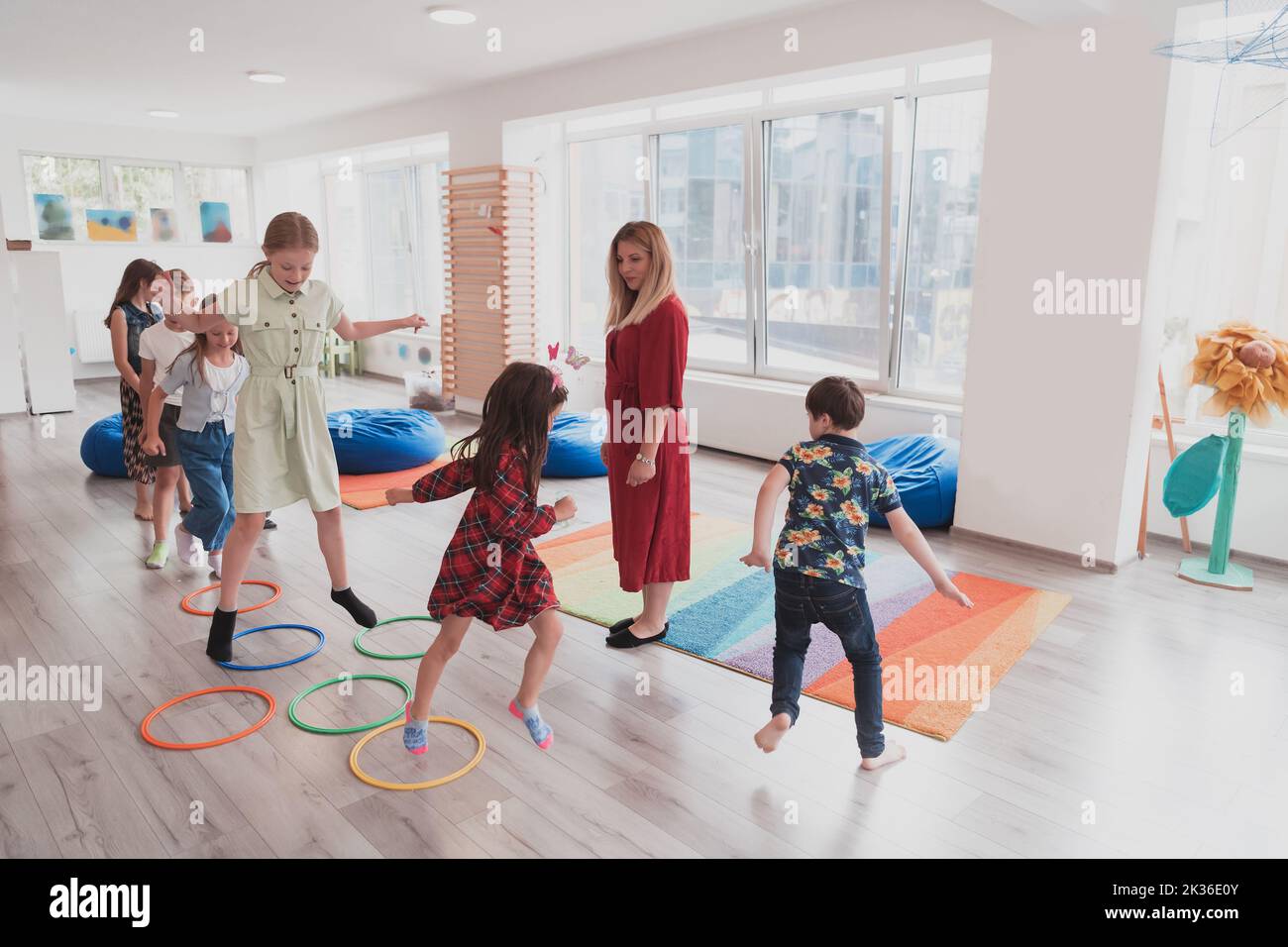Small nursery school children with female teacher on floor indoors in ...