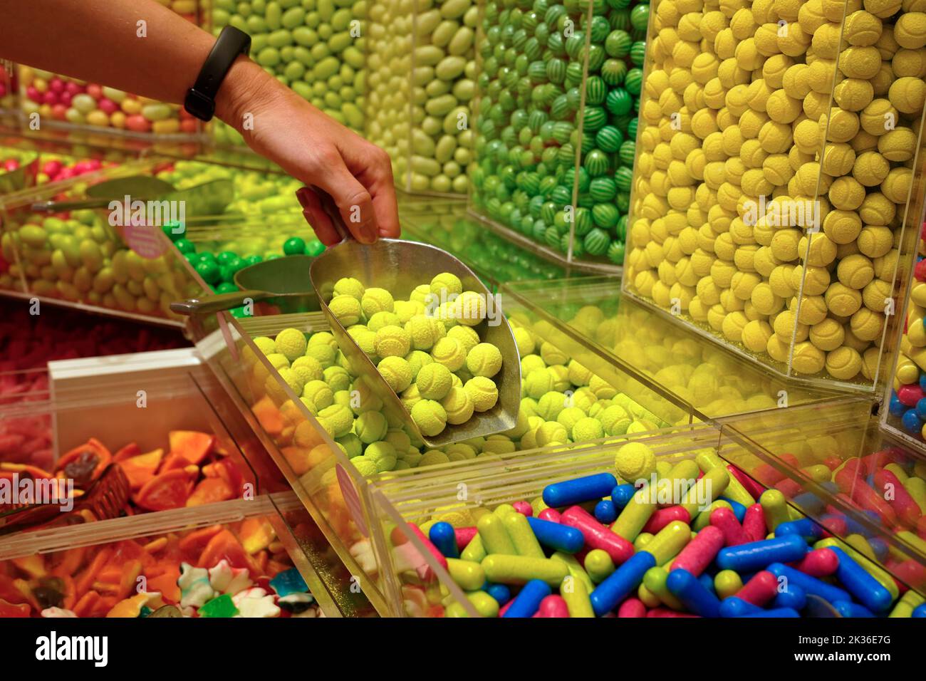 Woman hand with scoop taking colorful delicious candies on counter of ...