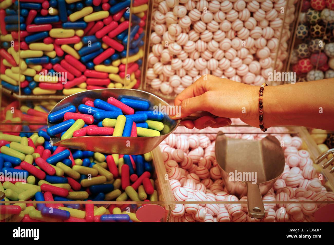 Woman hand with scoop taking colorful delicious candies on counter of ...