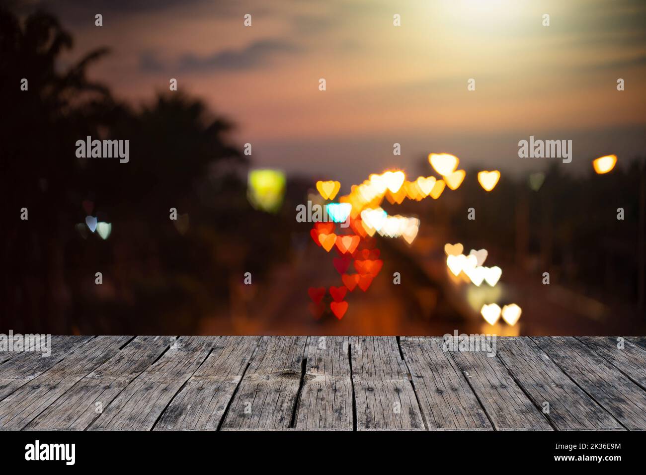 A wooden dock against a blurry background with heart-shaped city lights ...