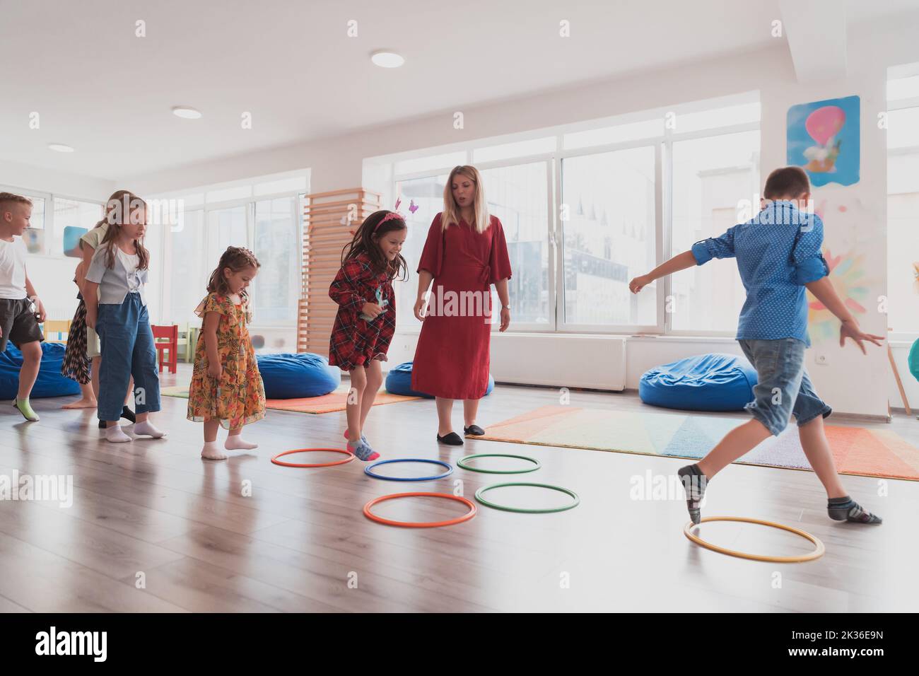 Small nursery school children with female teacher on floor indoors in ...