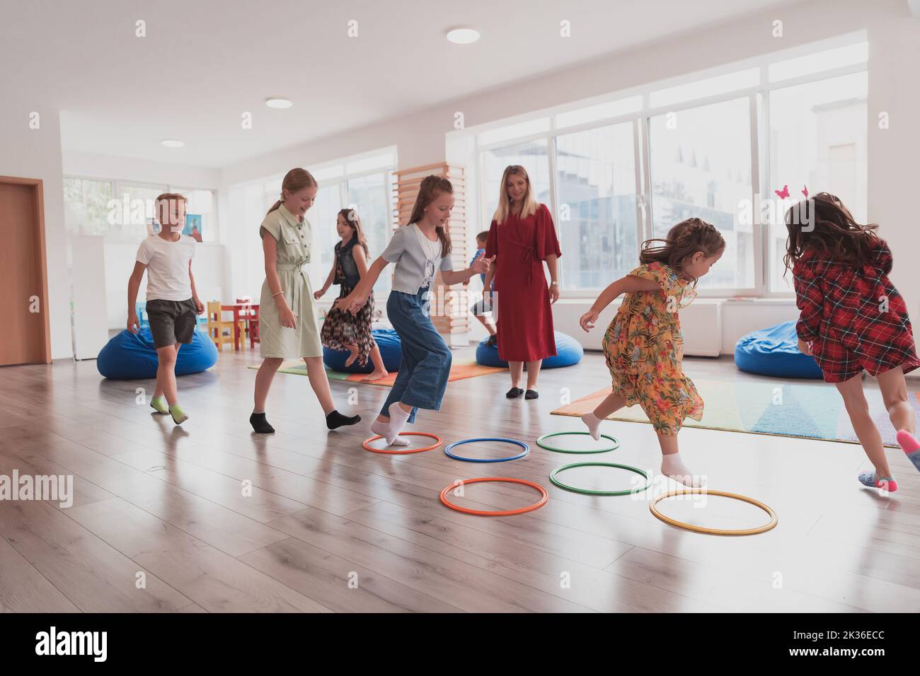 Small nursery school children with female teacher on floor indoors in ...