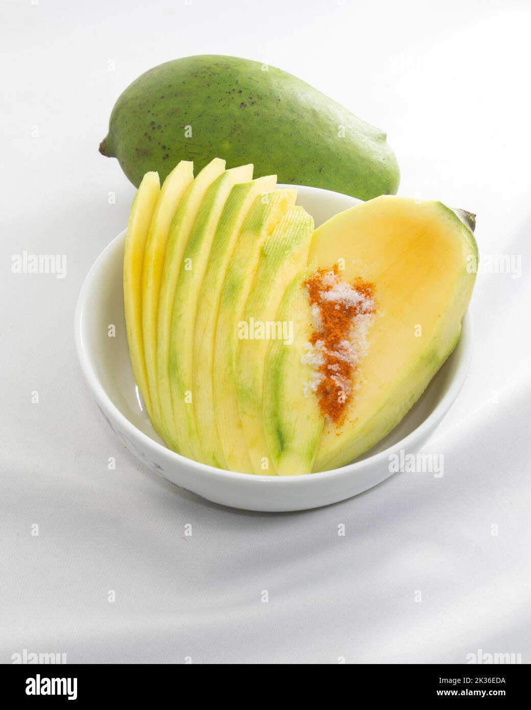 a unpeeled mango and mango slices with salt and chili powder. sour and ...