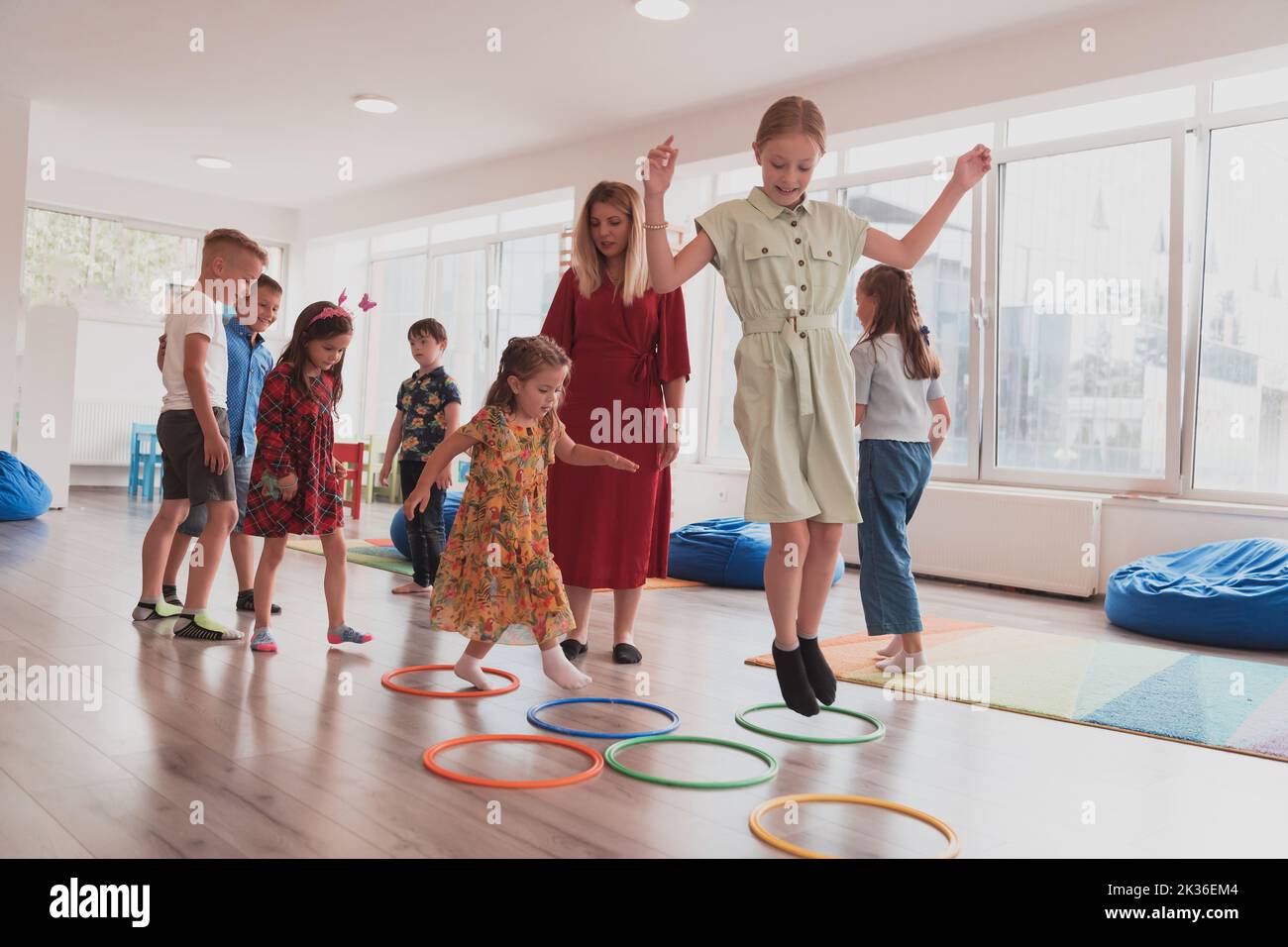Small nursery school children with female teacher on floor indoors in ...