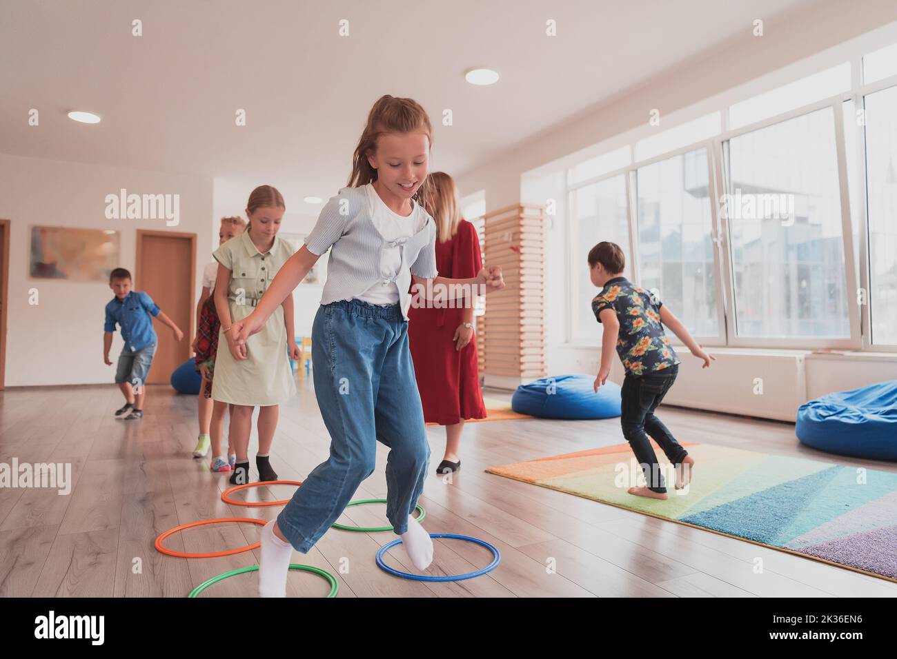 Small nursery school children with female teacher on floor indoors in ...