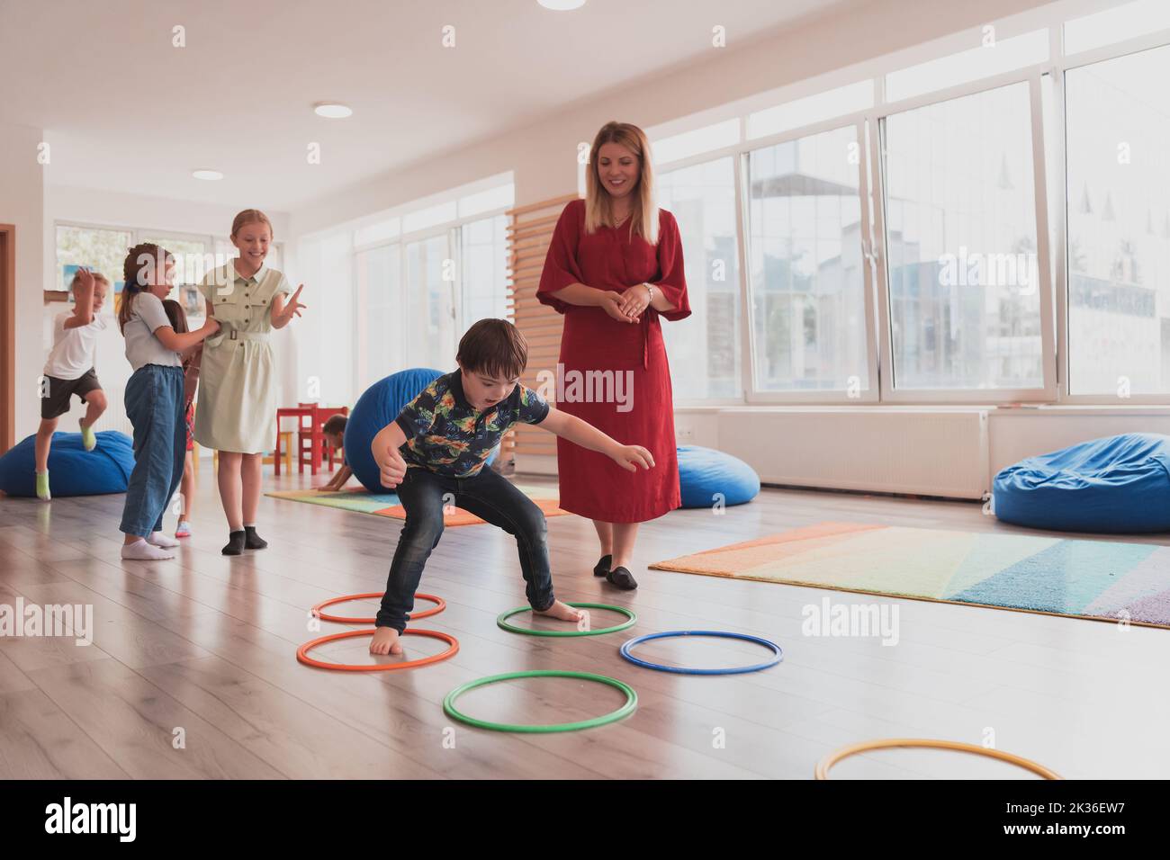 Small nursery school children with female teacher on floor indoors in ...