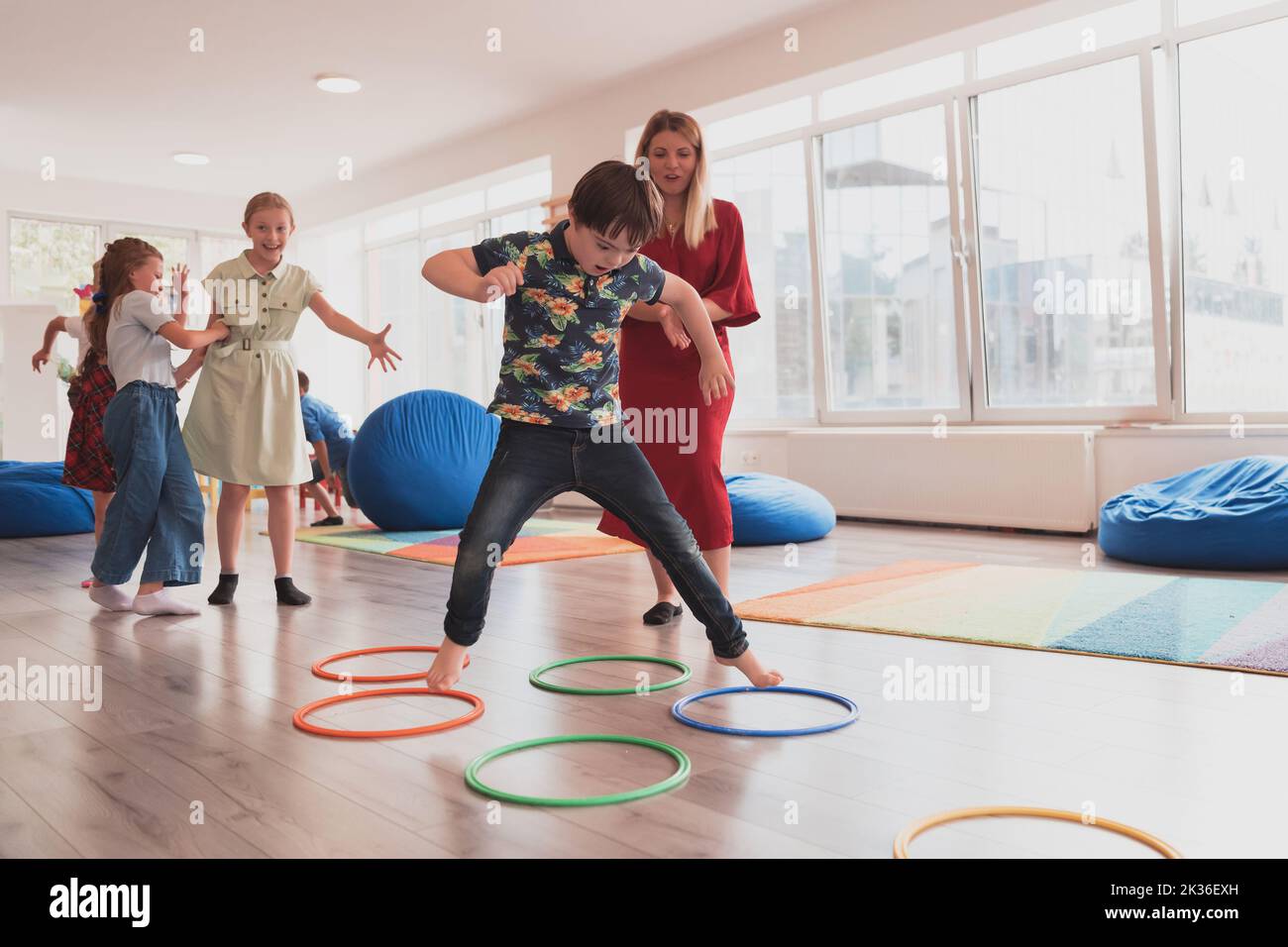 Small nursery school children with female teacher on floor indoors in ...