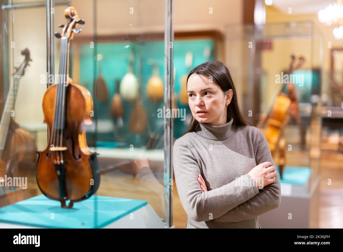 Interested brunette visiting exhibition of medieval musical instruments ...