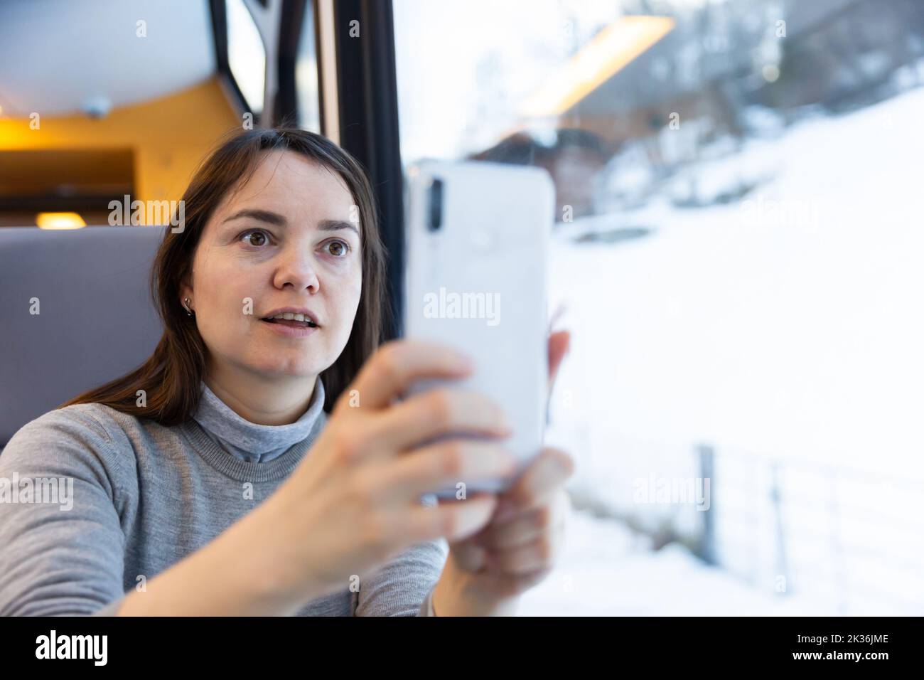 Woman taking photos with smartphone through window glass while ...