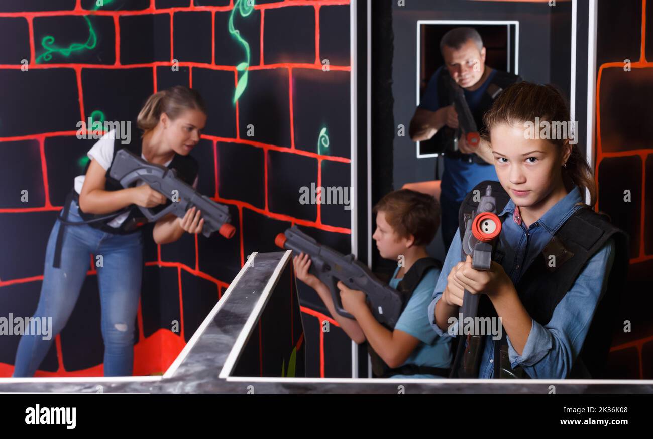 Active girl aiming laser gun at other players Stock Photo - Alamy