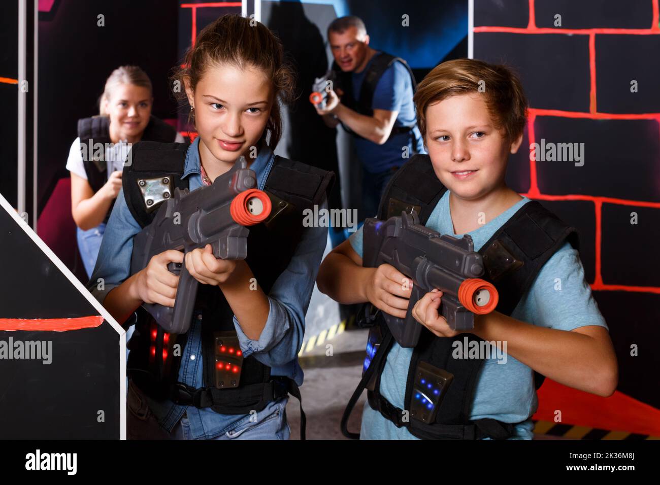 Happy teen brother and sister with laser pistols playing laser tag with their parents Stock ...
