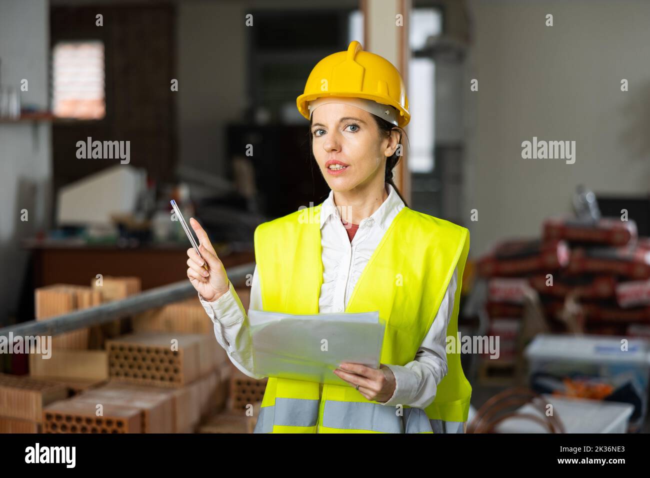 Female architect giving instructions to workers at construction site ...