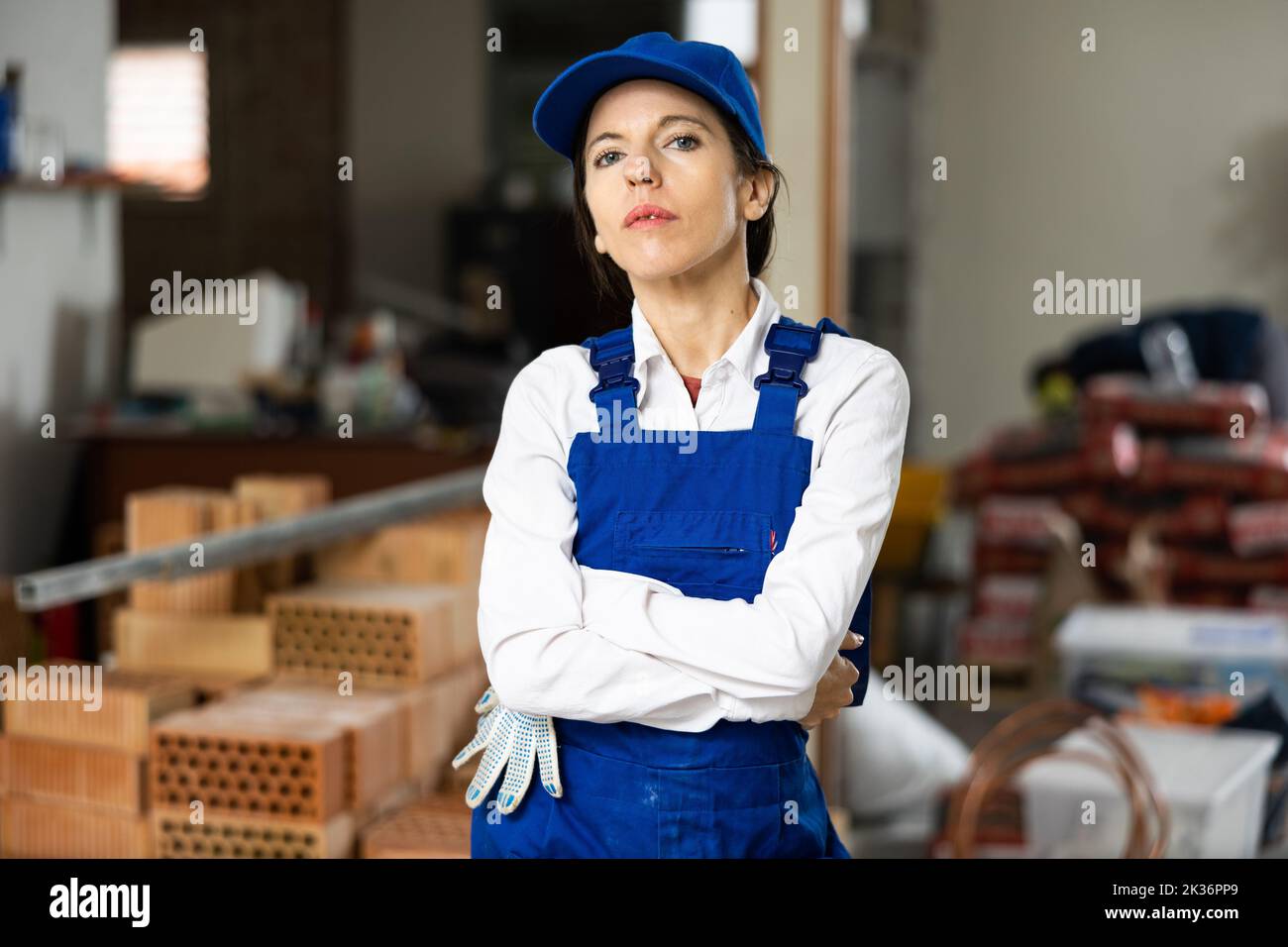 Portrait of confident female foreman in blue overalls in building under ...