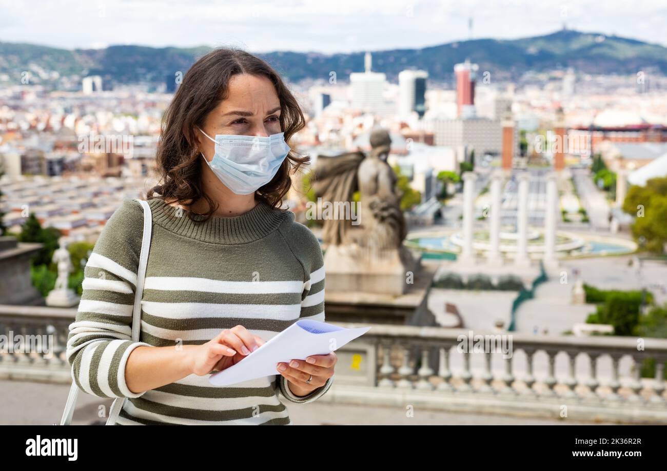 Girl traveler in protective mask with a guidebook in her hands on the ...