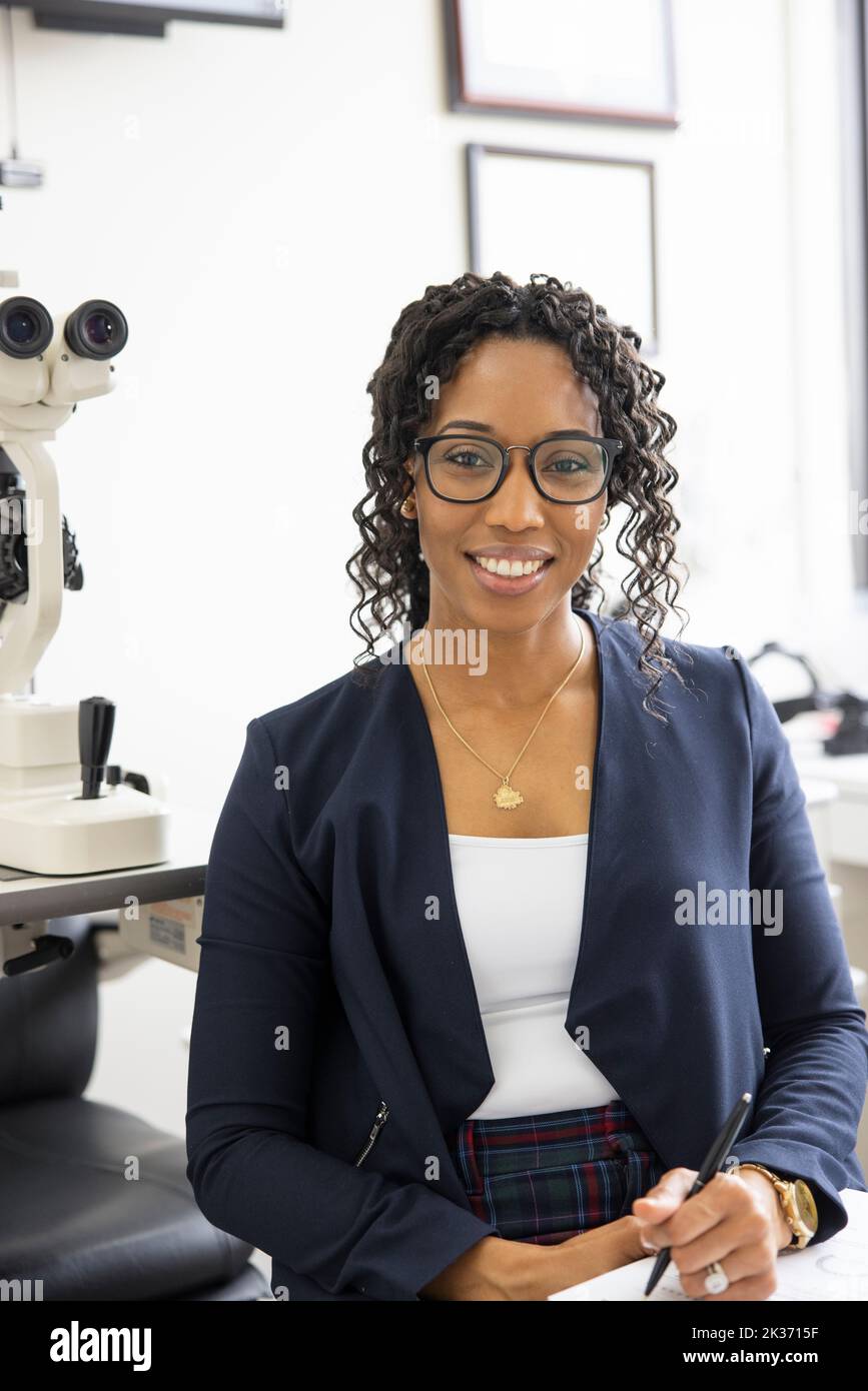 Portrait of a mid adult optometrist with female wearing glasses in ...