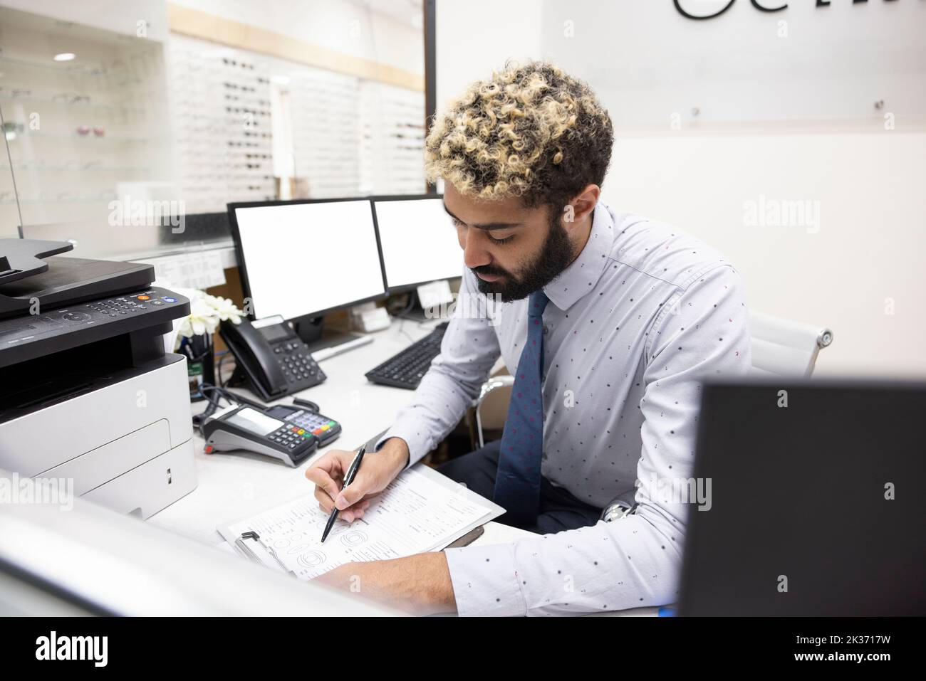 Male receptionist with clipboard working in optometry center Stock ...
