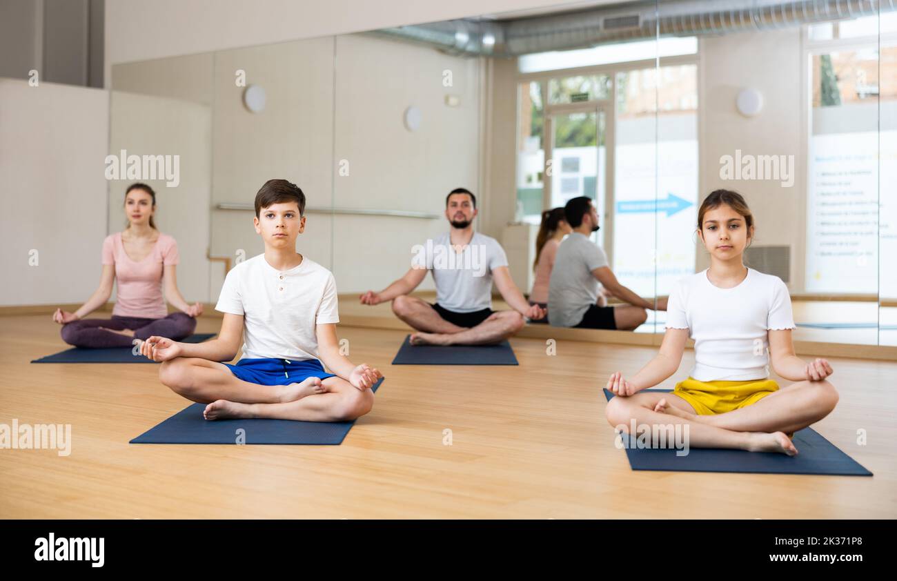 Family sitting in lotus pose in gym Stock Photo - Alamy
