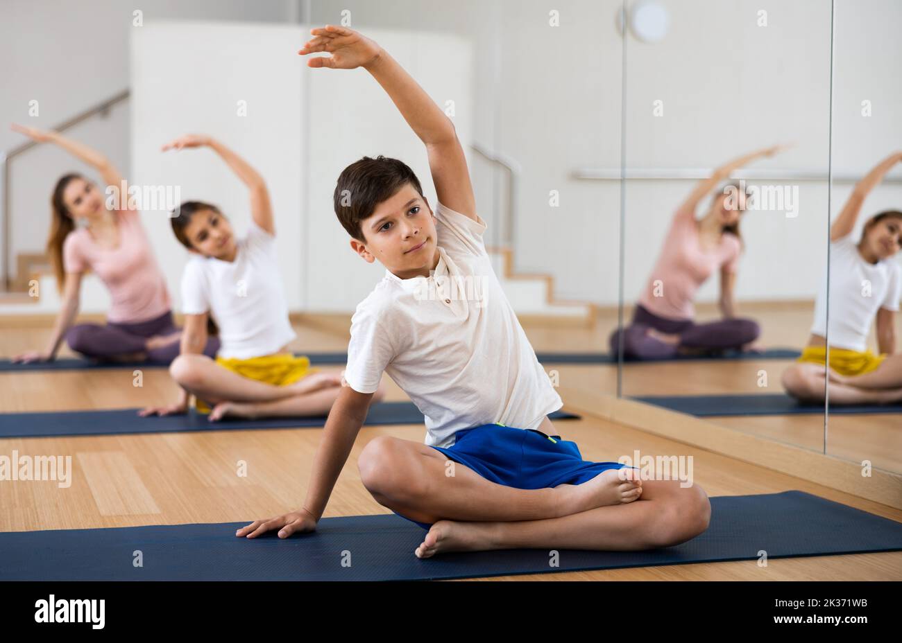 Tween boy doing stretching in lotus position during training with family Stock Photo - Alamy