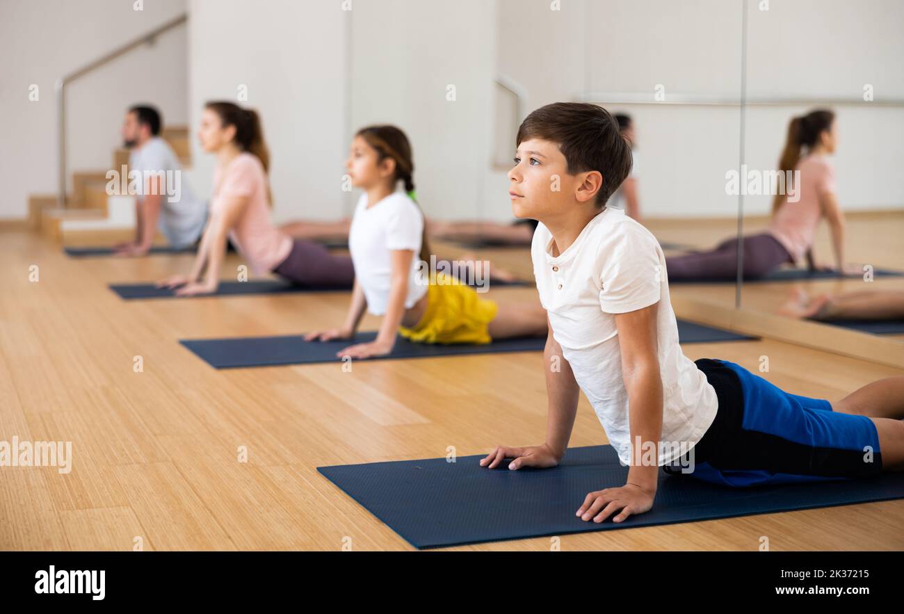 Boy doing stretching asana Bhujangasana during family yoga class Stock ...