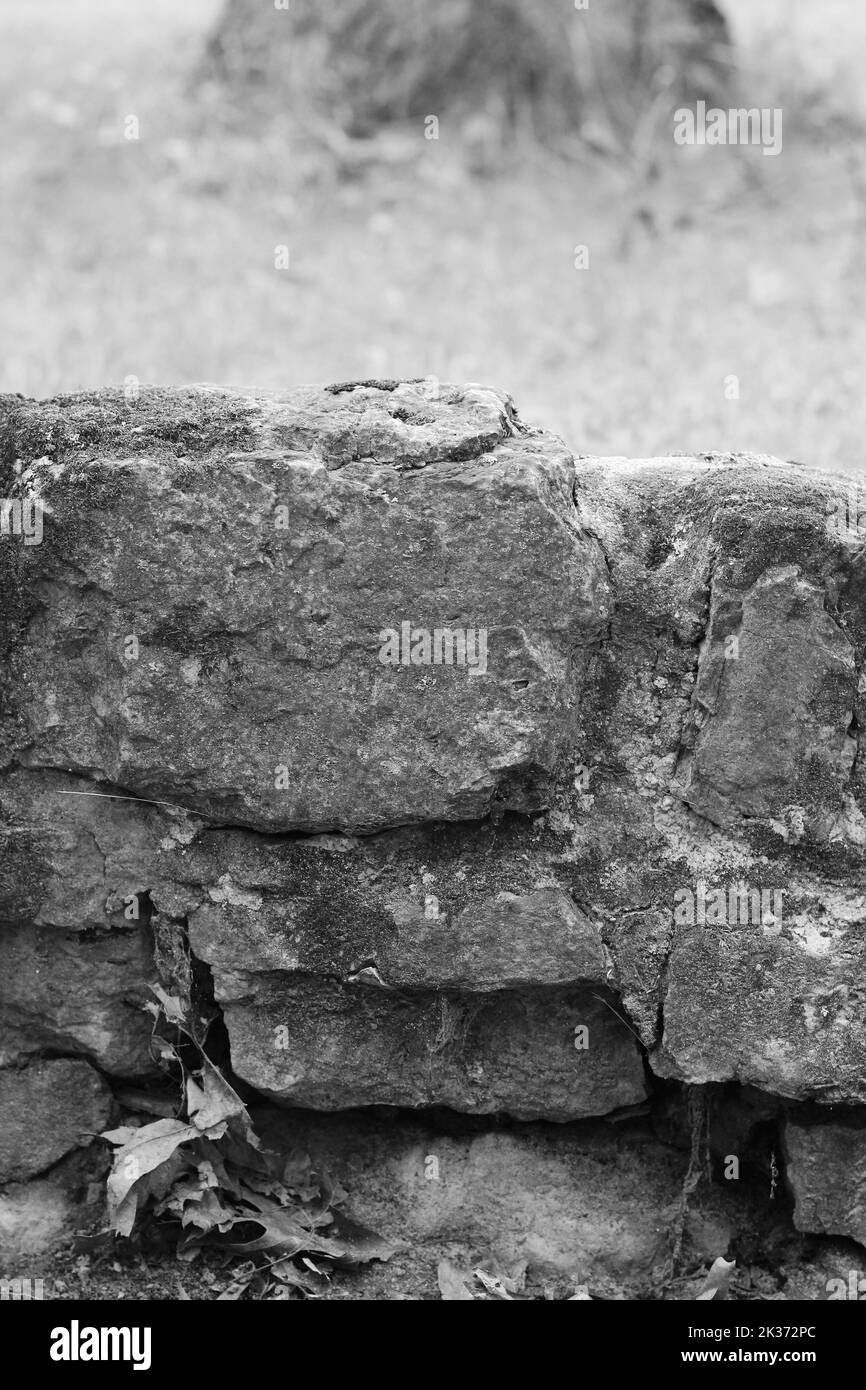 An old weathered stone fence crumbling from the years of use in a black ...