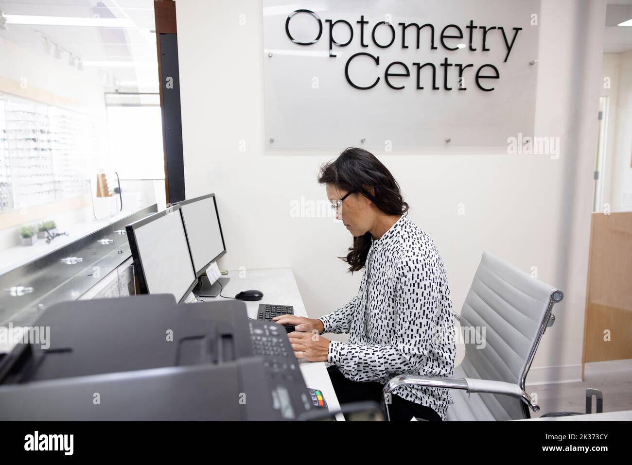 Female receptionist working at computer in optometry center Stock Photo ...