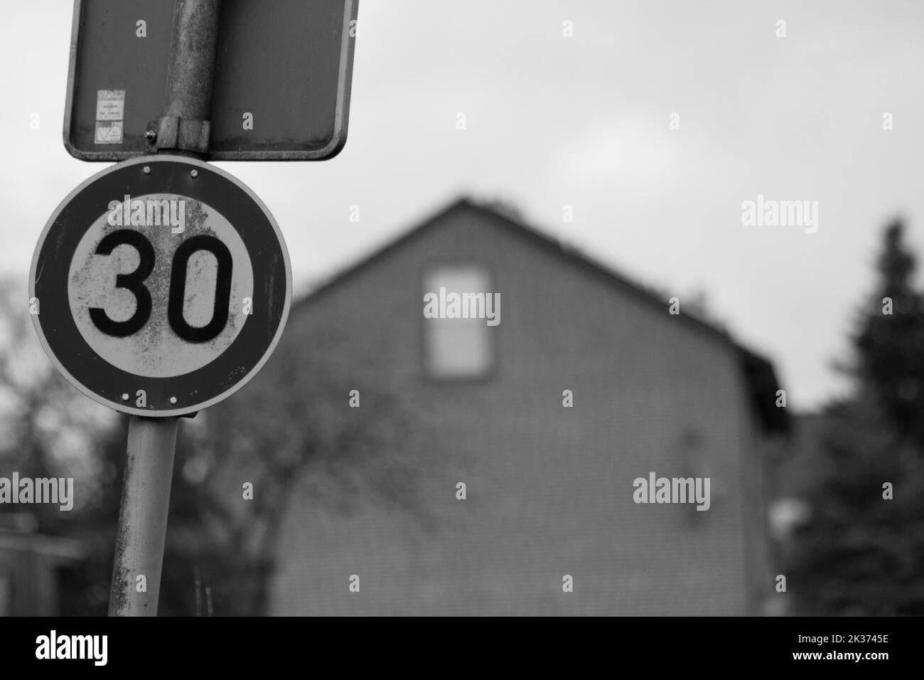 A grayscale of a traffic sign with a residential building in the ...