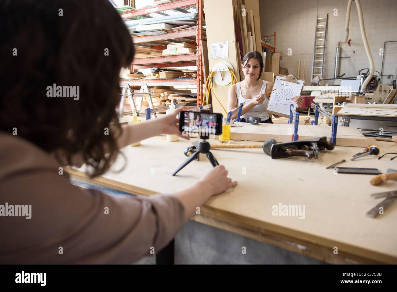 Female woodworker filming tutorial in wood shop Stock Photo - Alamy