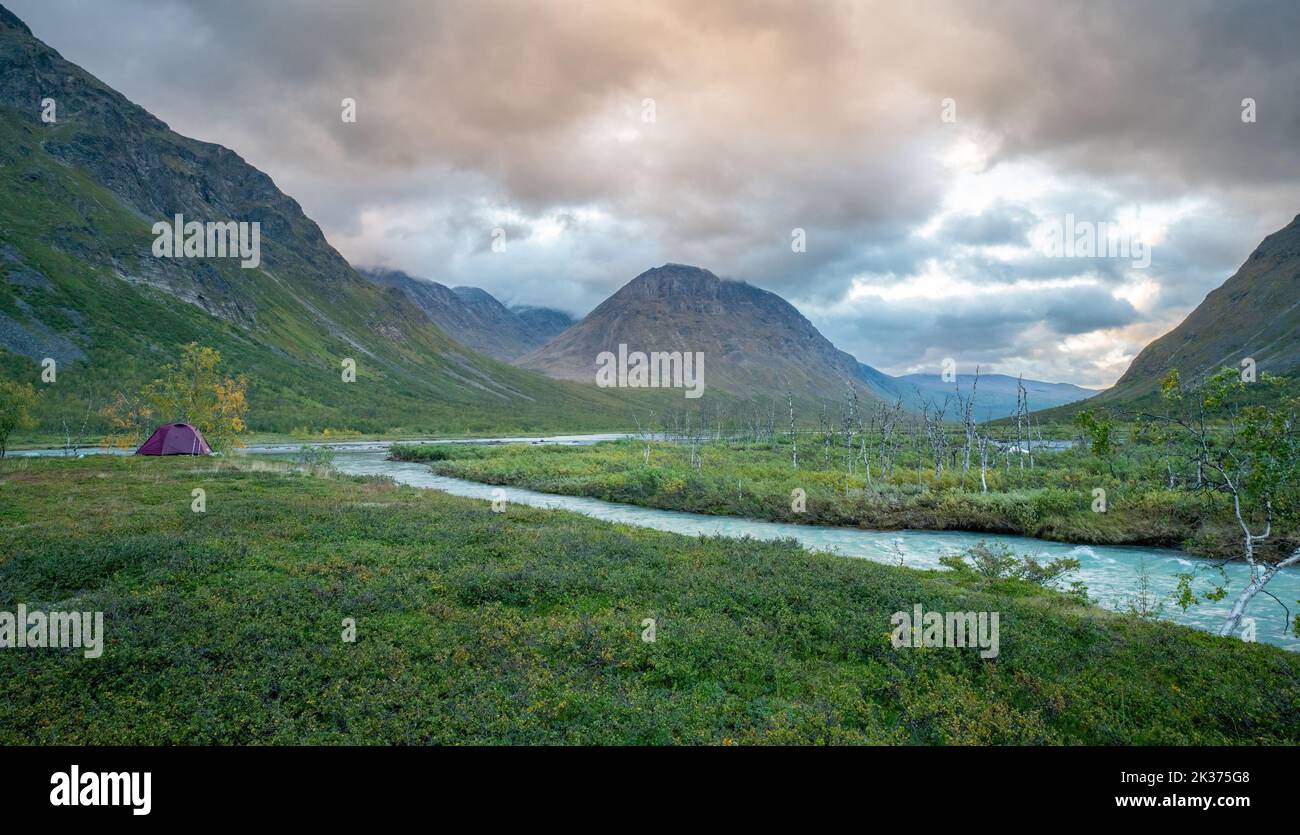 Outdoor tent in the remote Arctic valley under tall mountains of Sarek ...