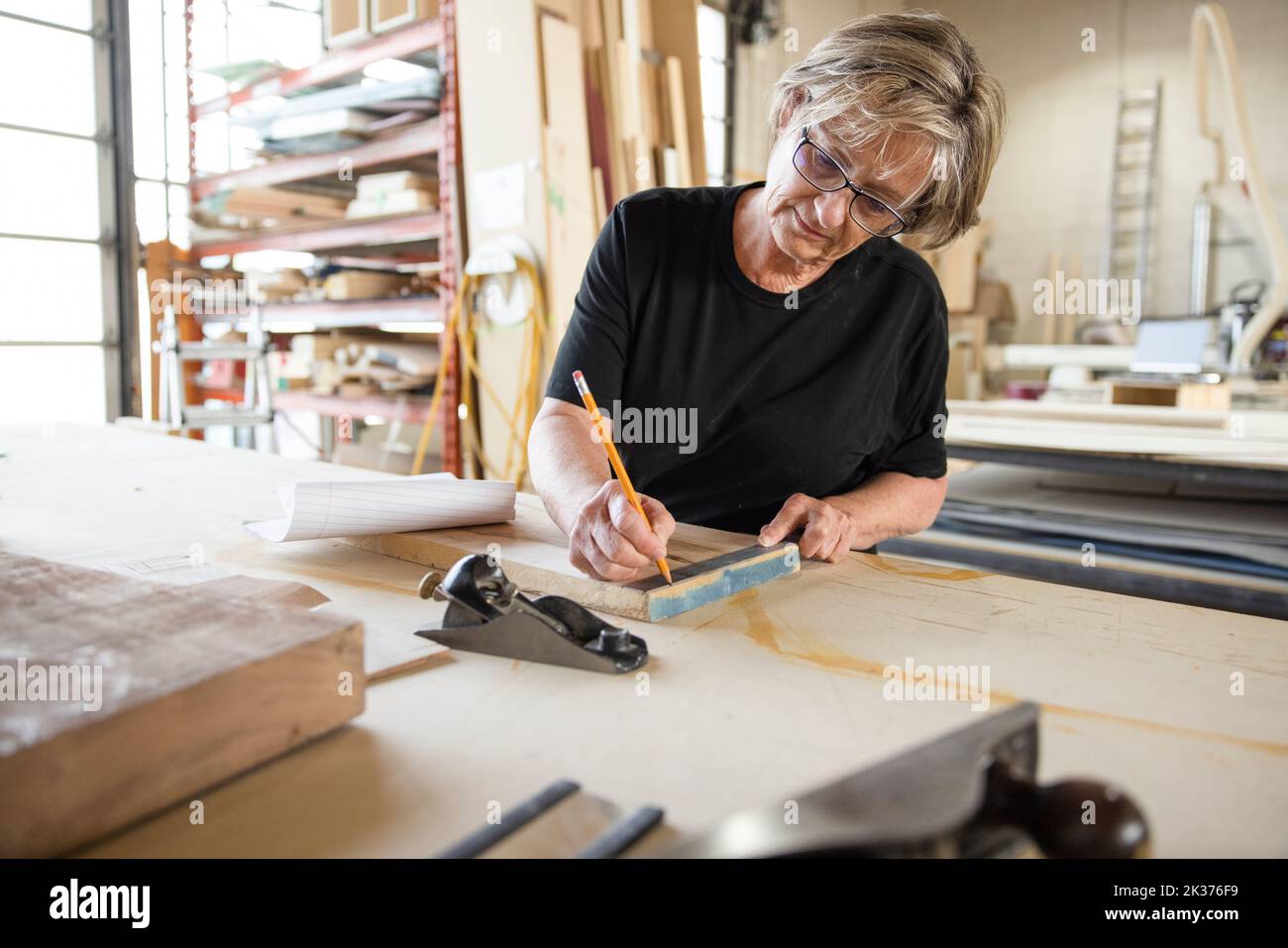 Senior female woodworker measuring wood piece in workshop Stock Photo ...
