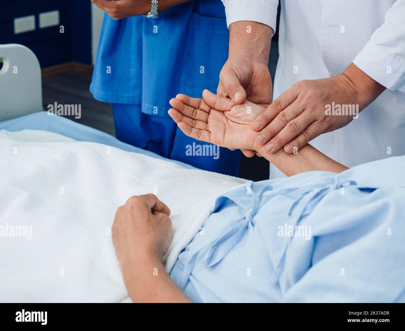 Doctor's hand in white lab coat is holding elderly patient's hand lying ...