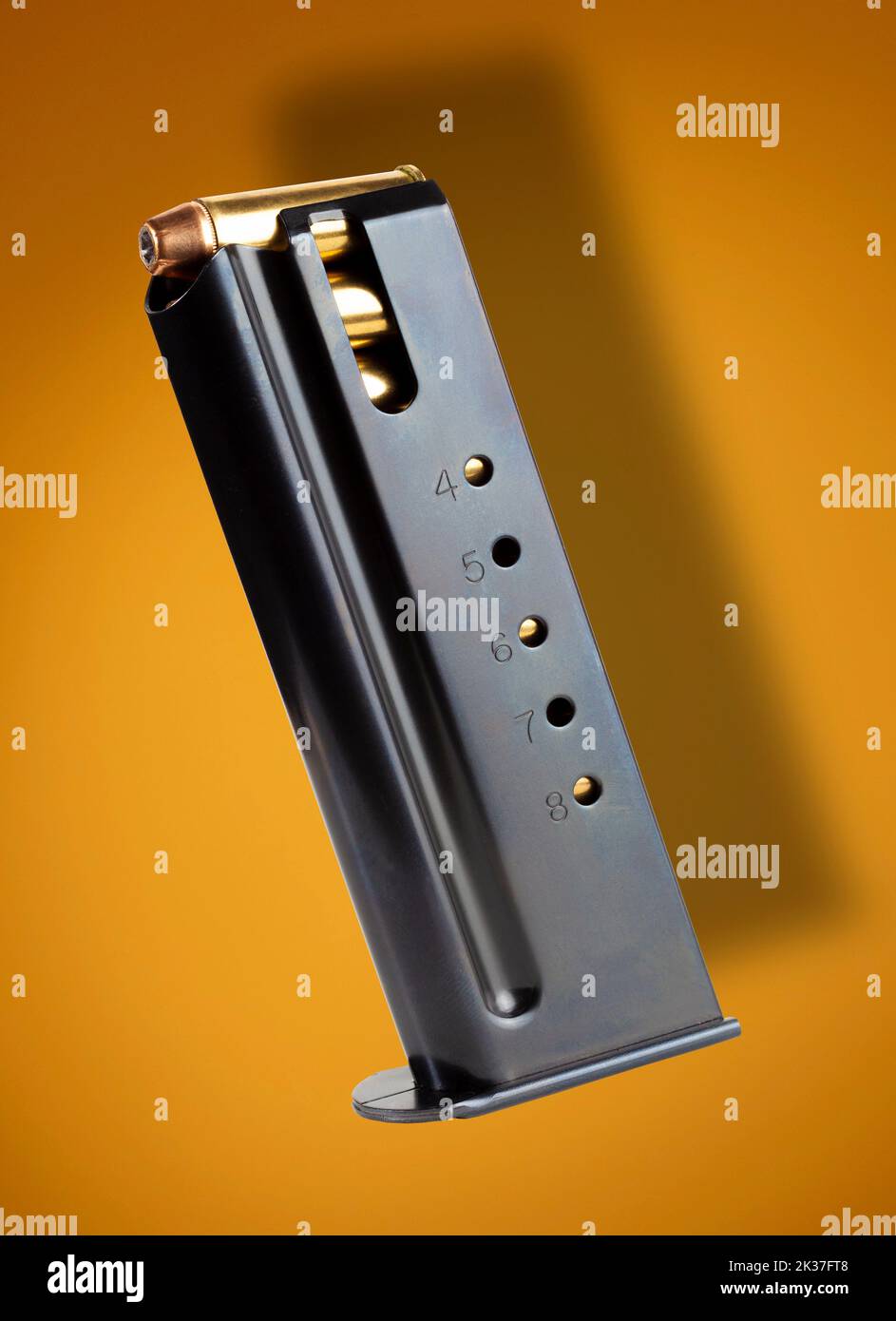 Loaded semi auto pistol magazine on orange with drop shadow behind ...