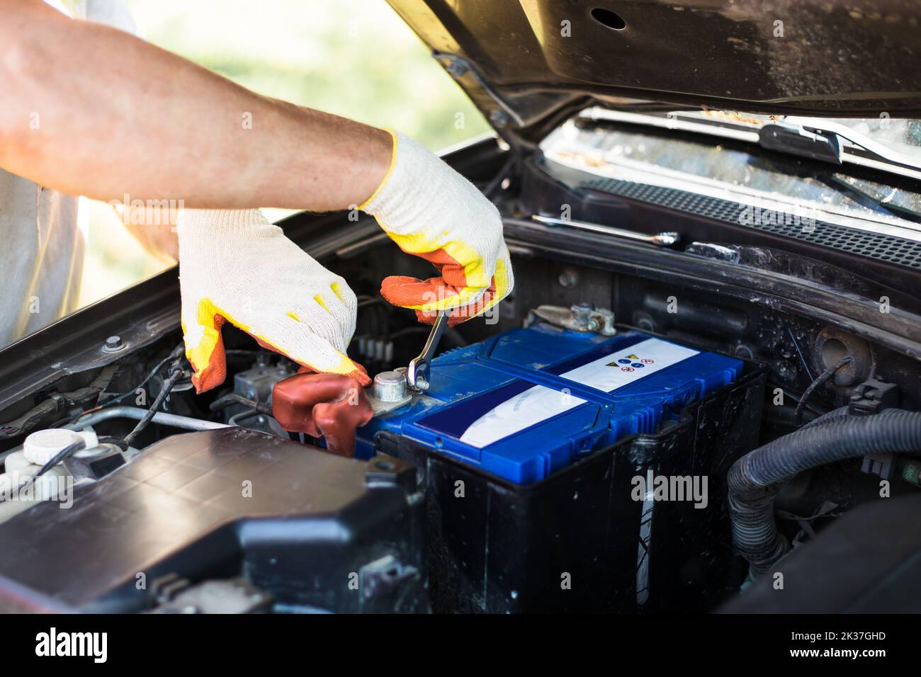 Replacing the battery in a car. The mechanic unscrews the battery ...