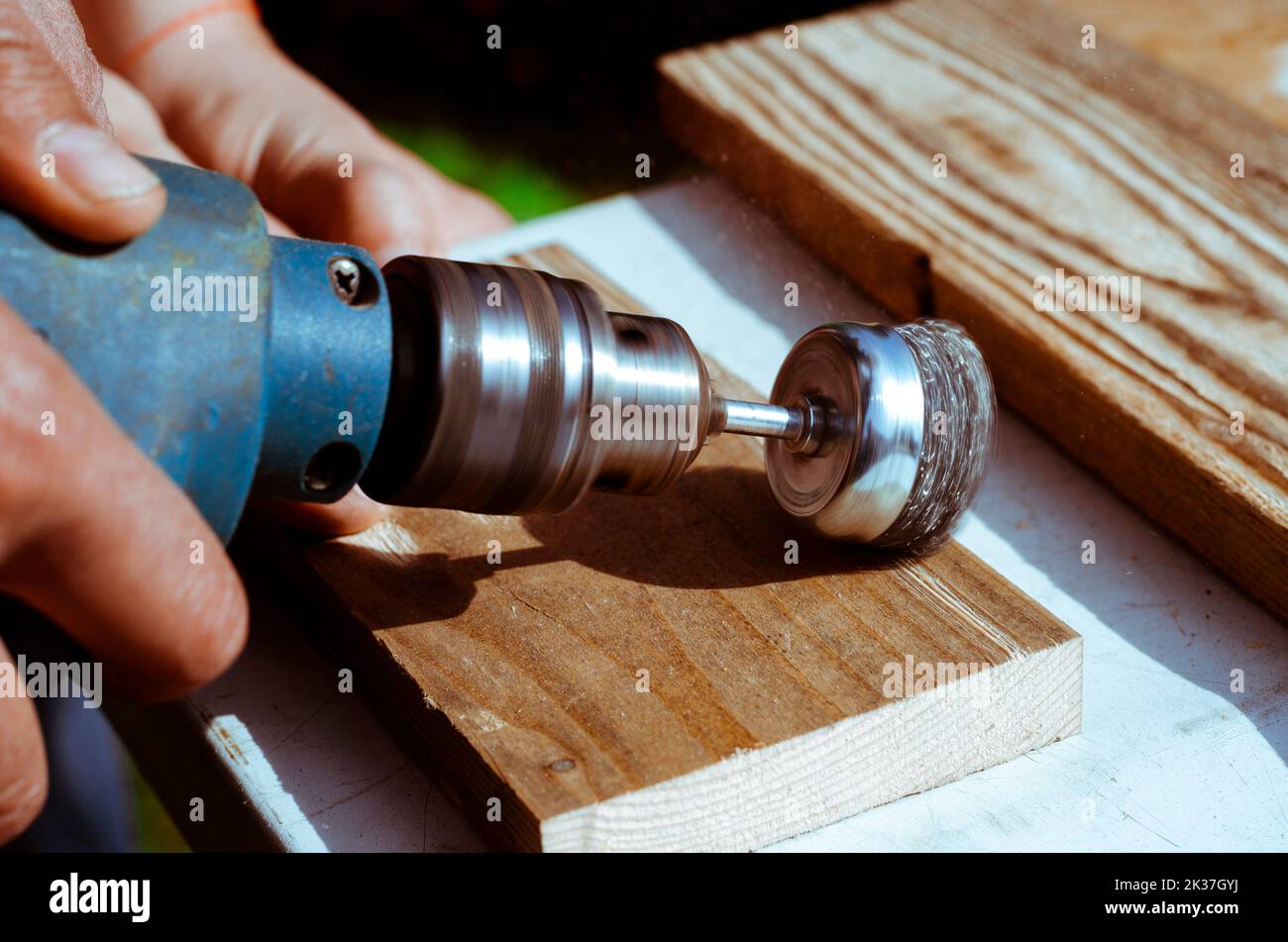 Hands man with electrical rotating brush metal disk sanding a piece of ...