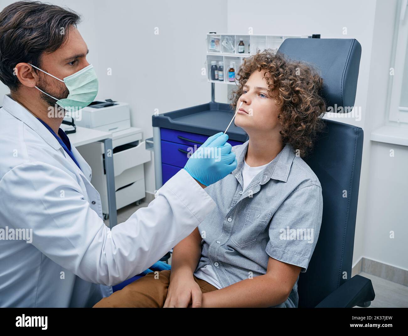 doctor taking nasopharyngeal swab of curly boy for examination in ...