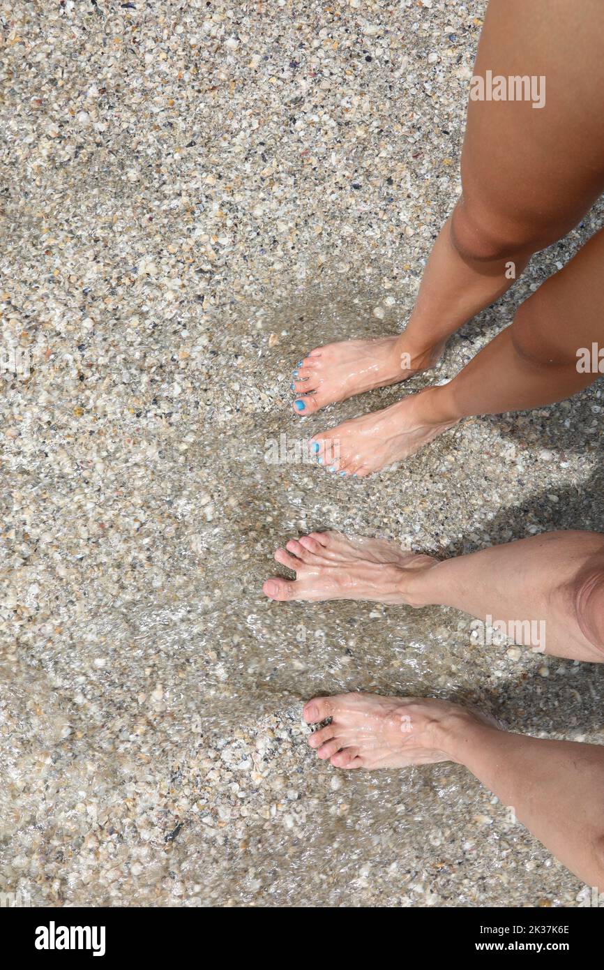 four barefoot feet on the seashore and many shells in the summer Stock ...
