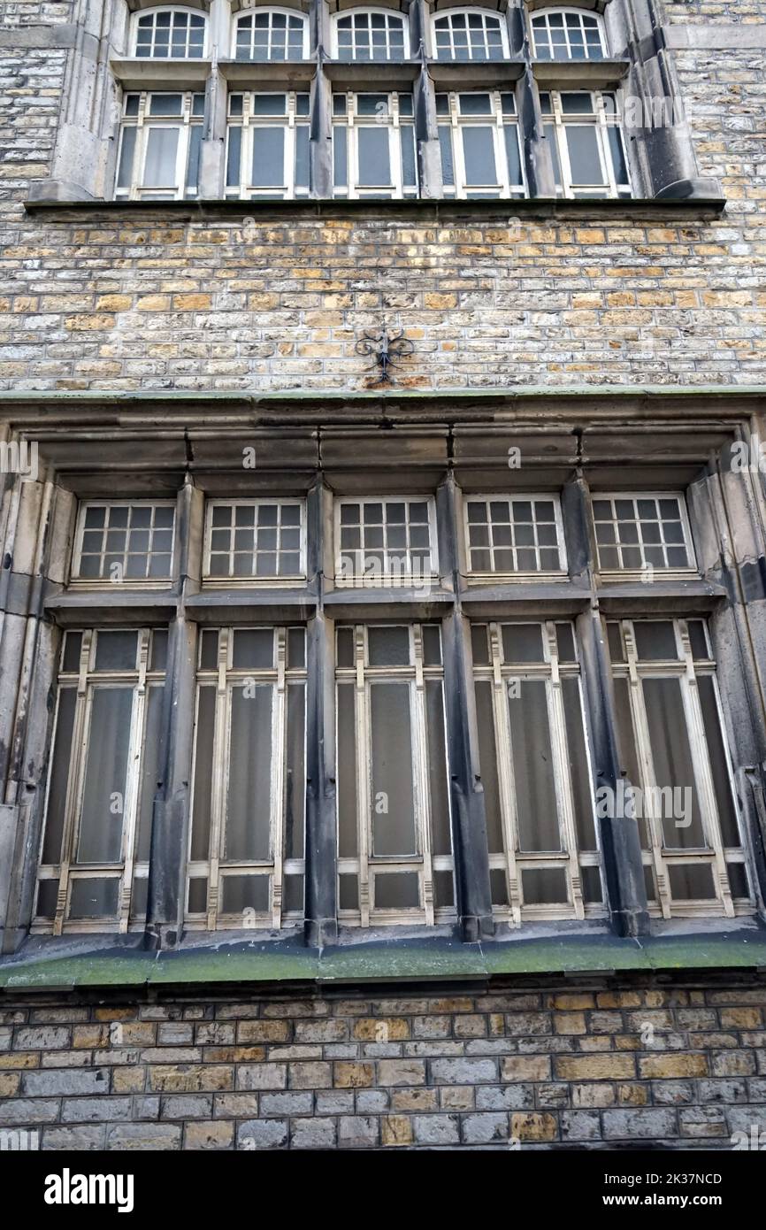 A vertical low angle of old wooden windows on a stone brick facade of a ...
