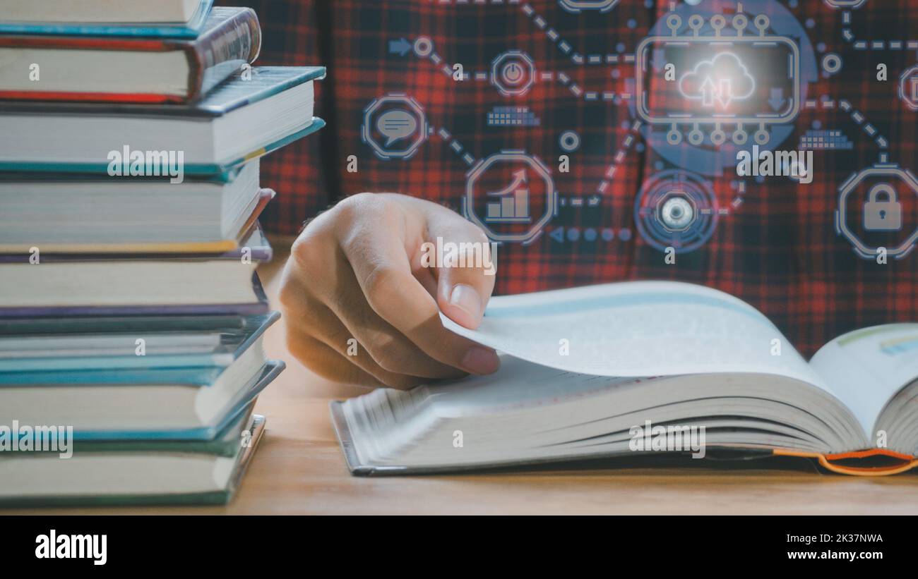 Asian young man opening and reading and pointing a book near book piles ...