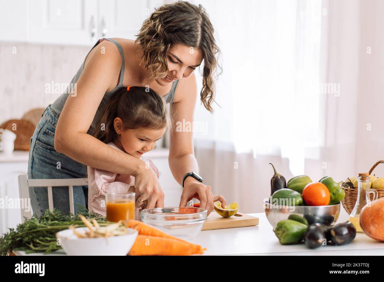 Mom and daughter cook food together slicing vegetables Stock Photo - Alamy