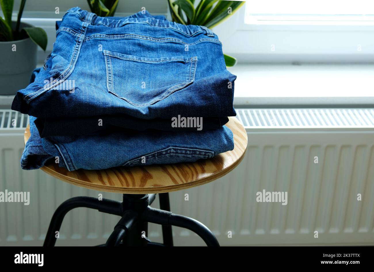 stack of blue denim jeans on stool in bedroom aganst window Stock Photo ...
